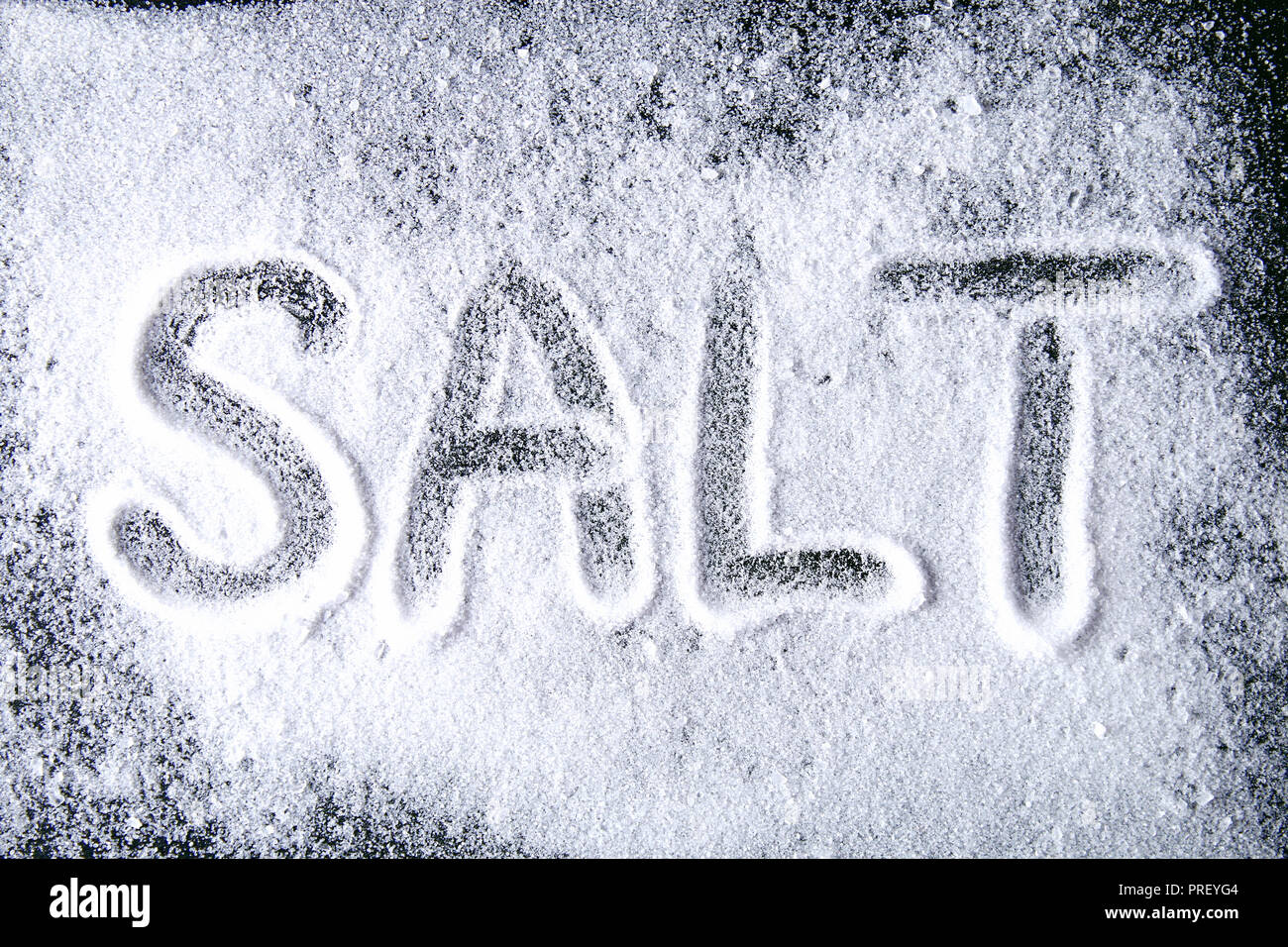 The word salt is written on small crystals of salt scattered on a black ...