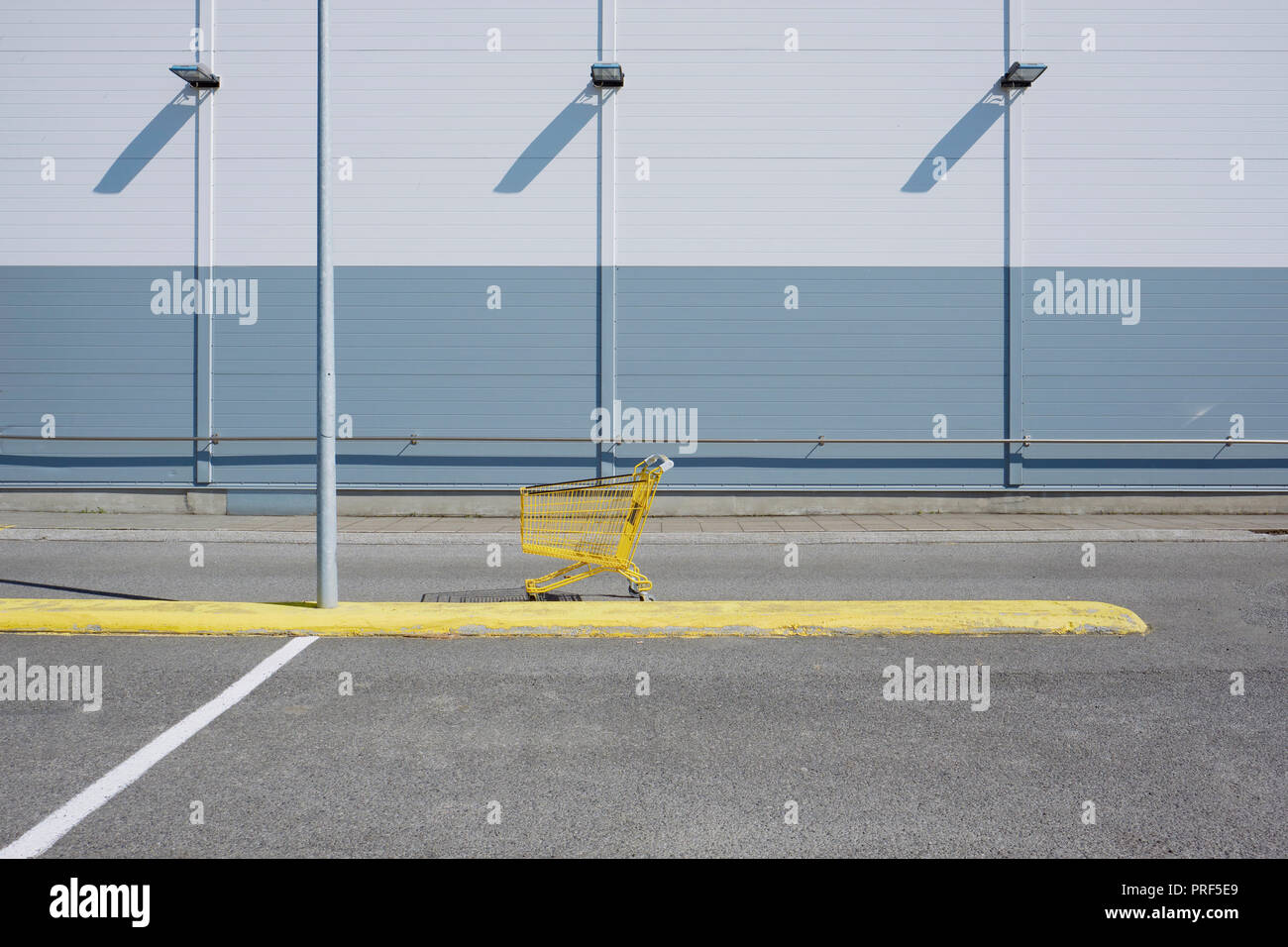 A single yellow shopping cart / trolley in an empty supermarket car ...