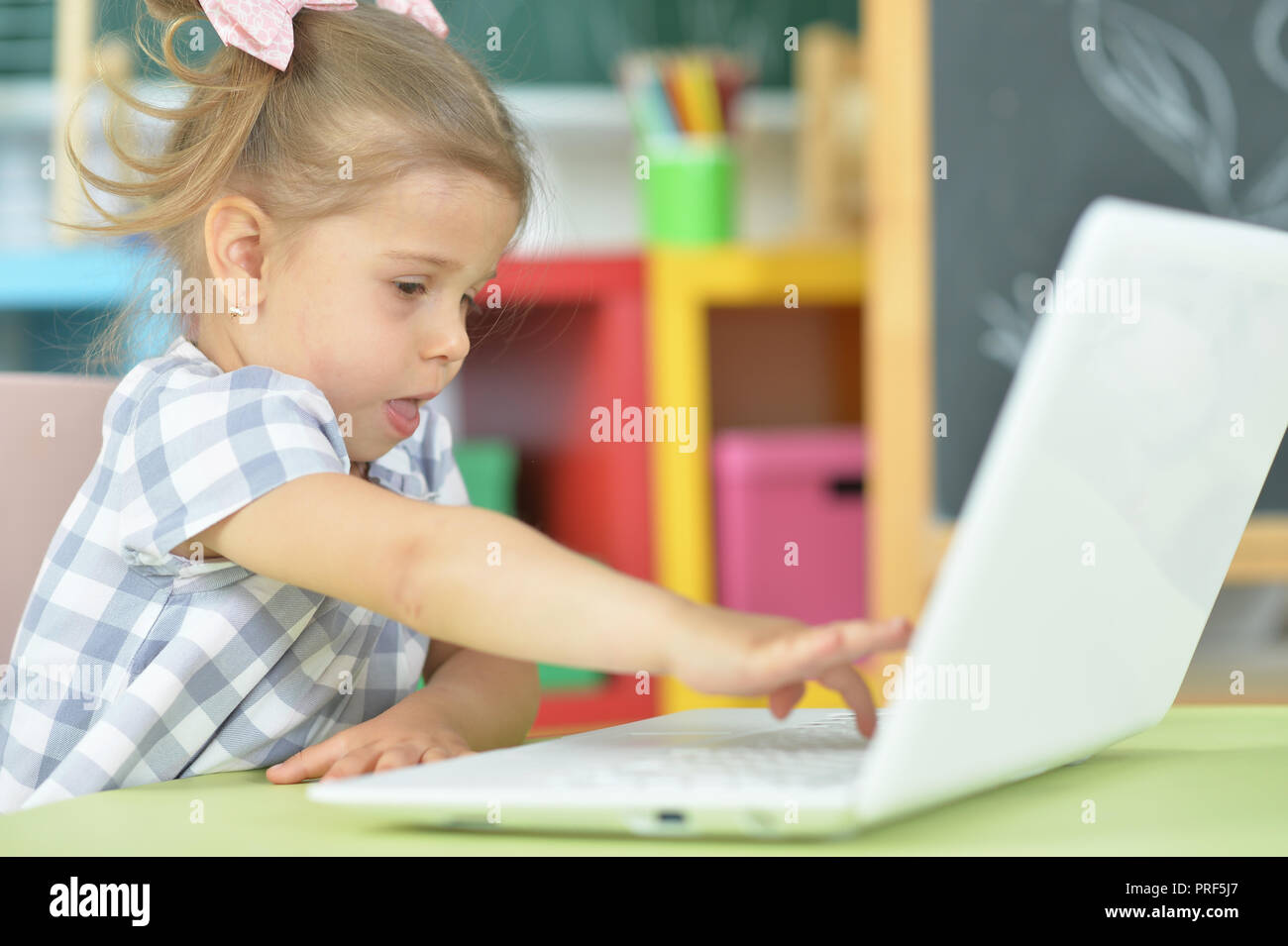 Curious little girl using laptop at desk Stock Photo - Alamy
