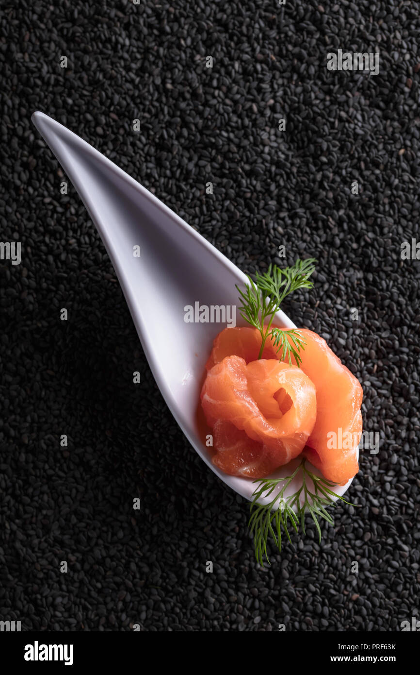 Slice of salted salmon with dill on the background of black sesame. Top ...