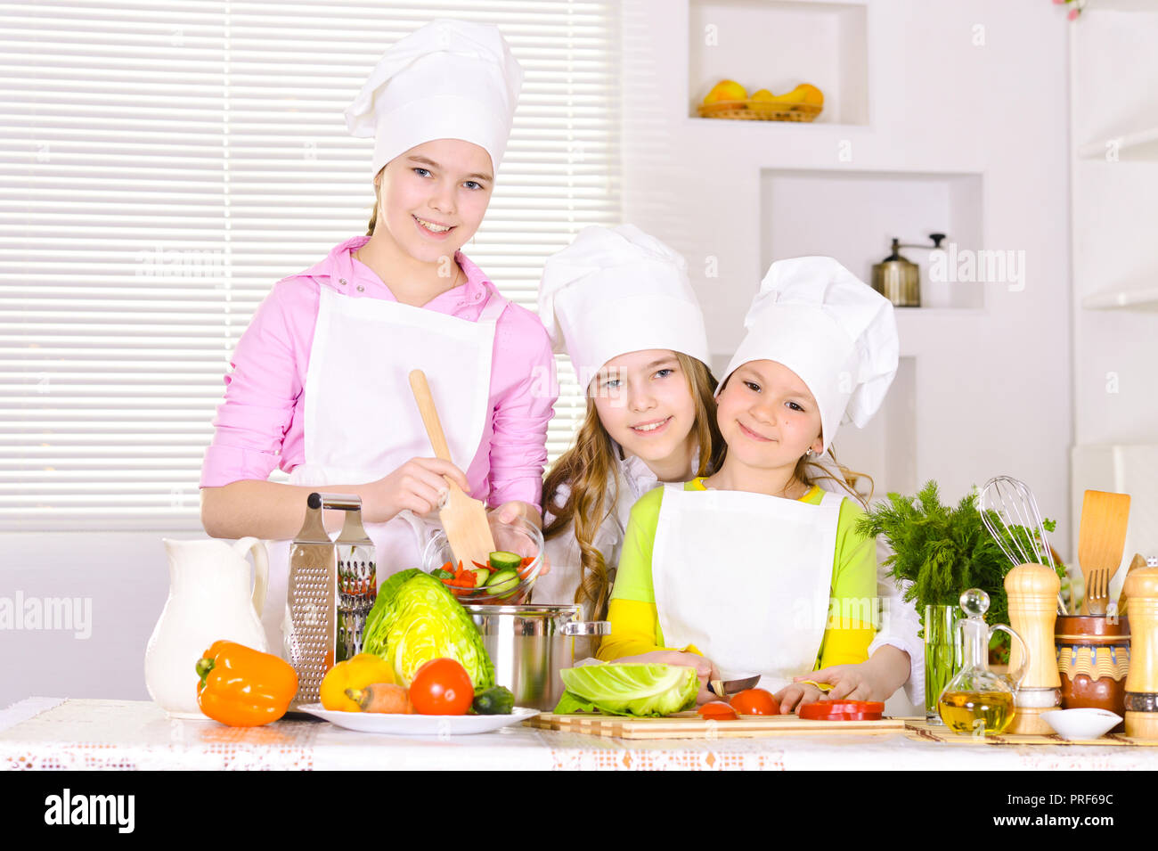 happy cute girls cooking vegetable dish on kitchen Stock Photo - Alamy