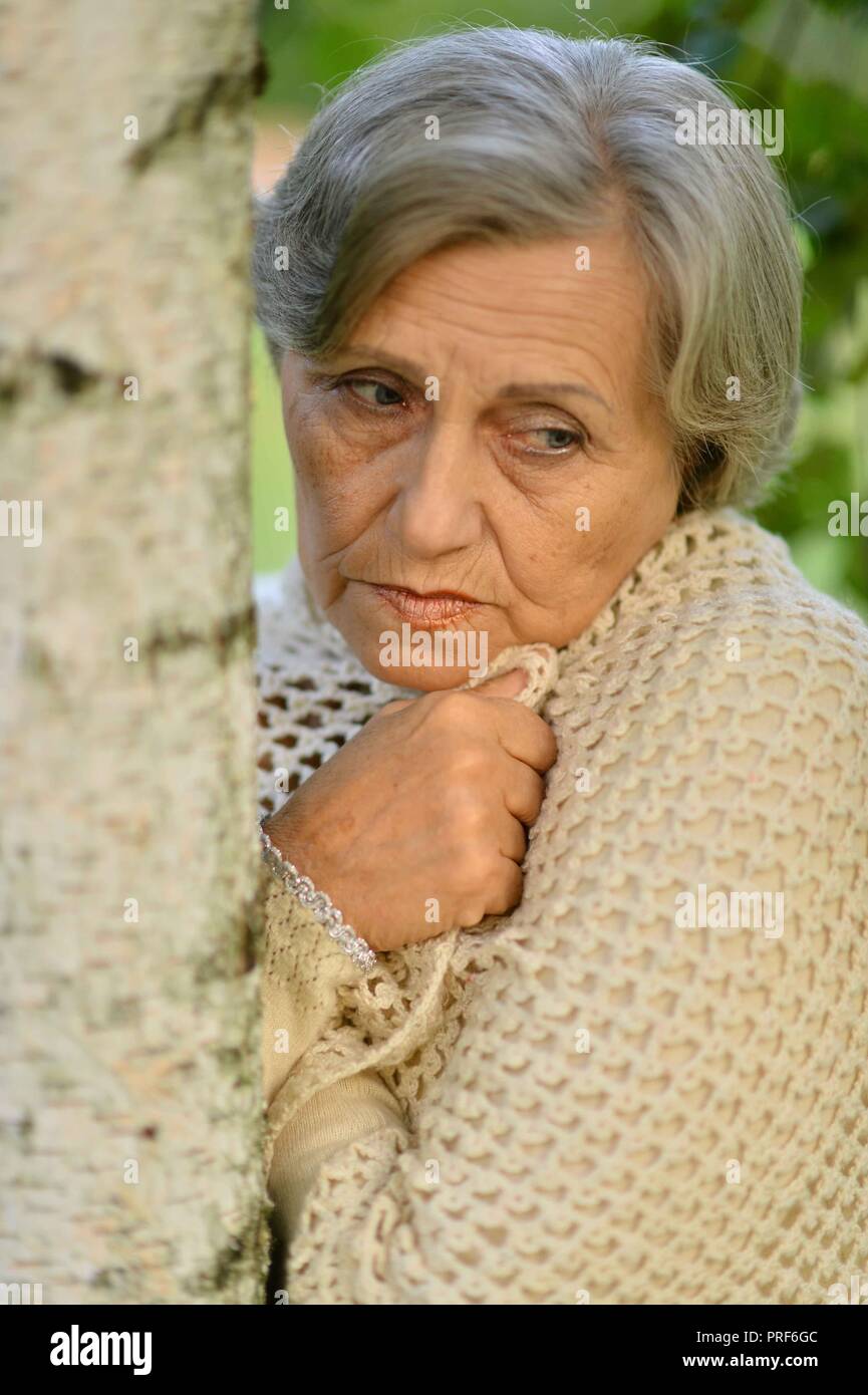 sad senior woman standing by the tree Stock Photo - Alamy