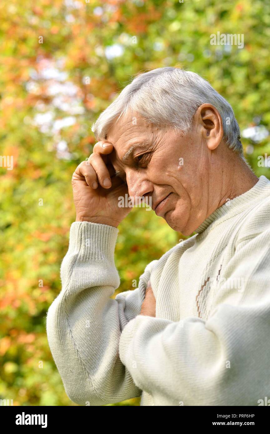 Serious senior man in park on green background Stock Photo - Alamy