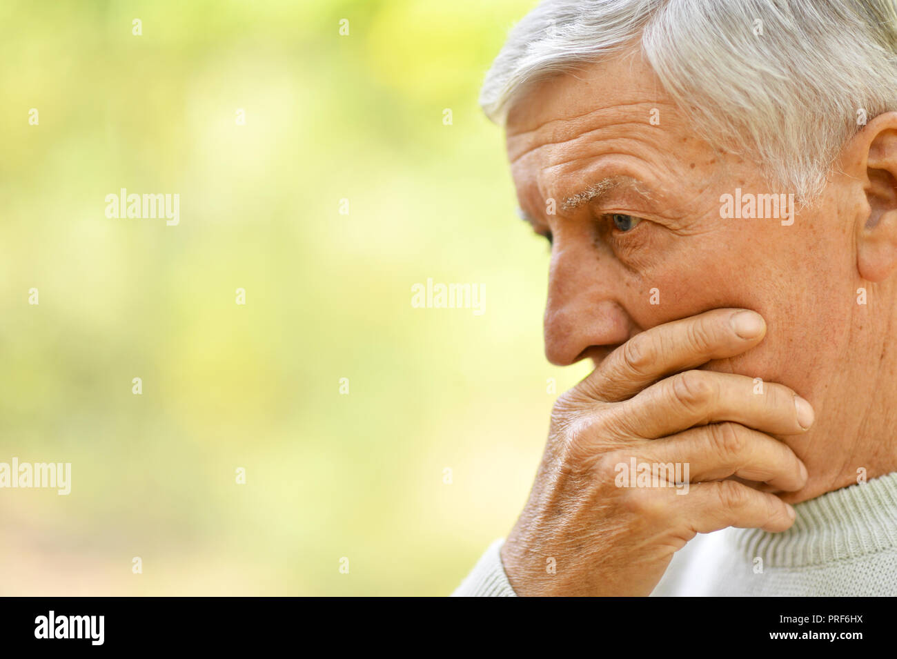 Serious senior man in park on green background Stock Photo - Alamy