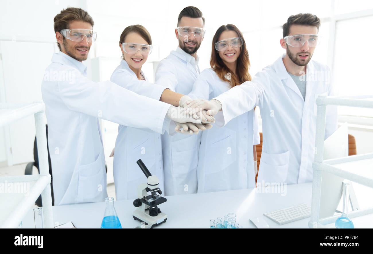successful team of young scientists with hands clasped together Stock ...