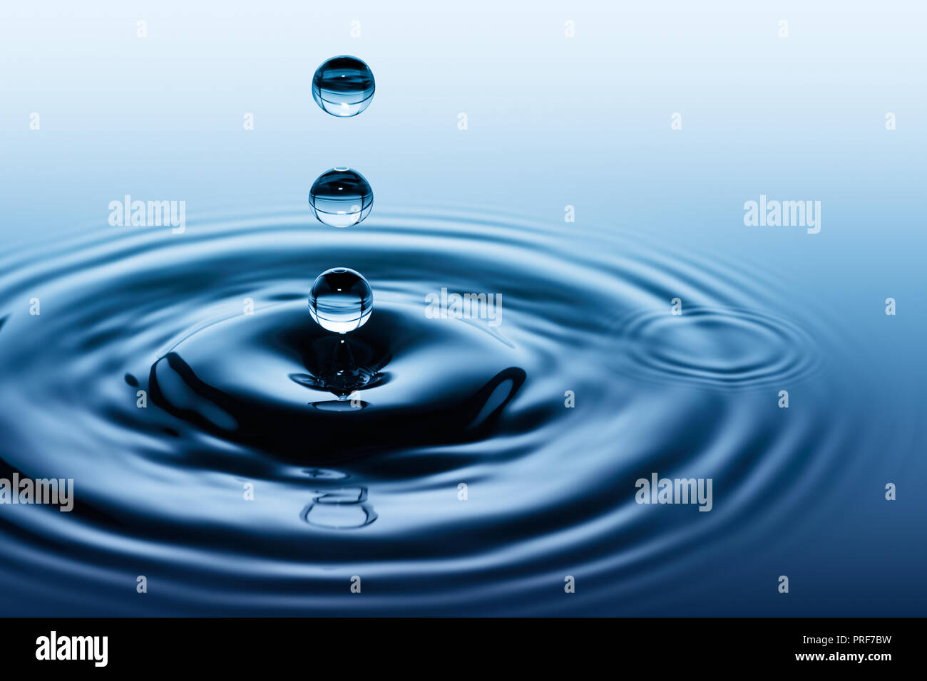 Splash. Rain drops falling on smooth surface of water Stock Photo - Alamy