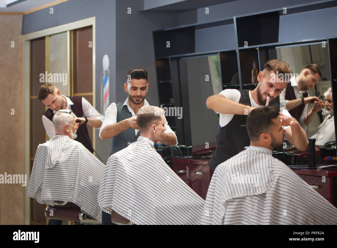 Process of three professional barbers working with clients' hair in ...