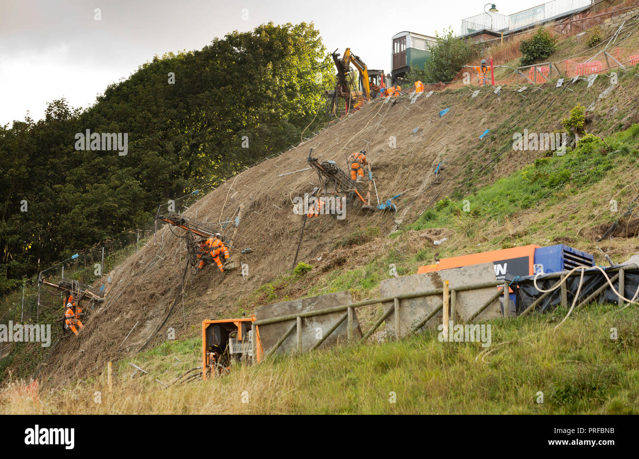 Construction engineers in harnesses fixed by long cables work on a ...