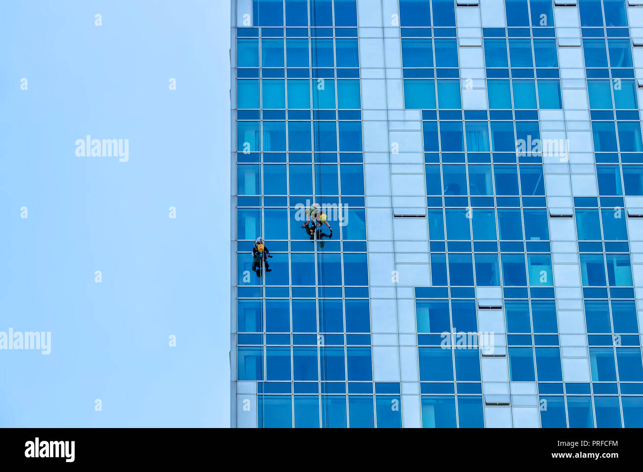 Window washers cleaning the glass facade of a modern building, high ...