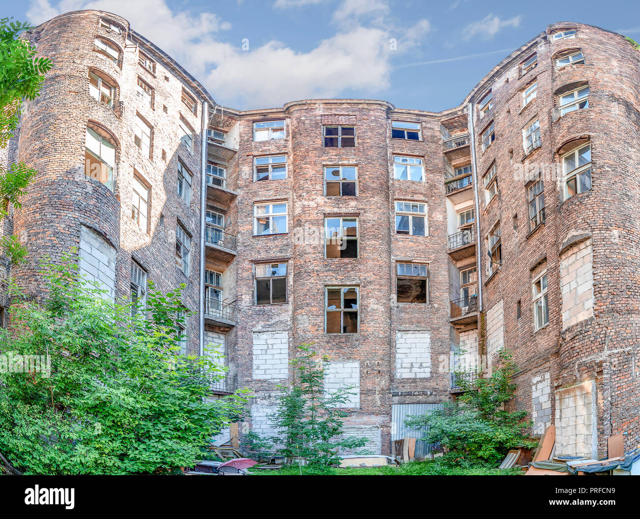 Facade of ruined old vintage red brick house with broken windows ...