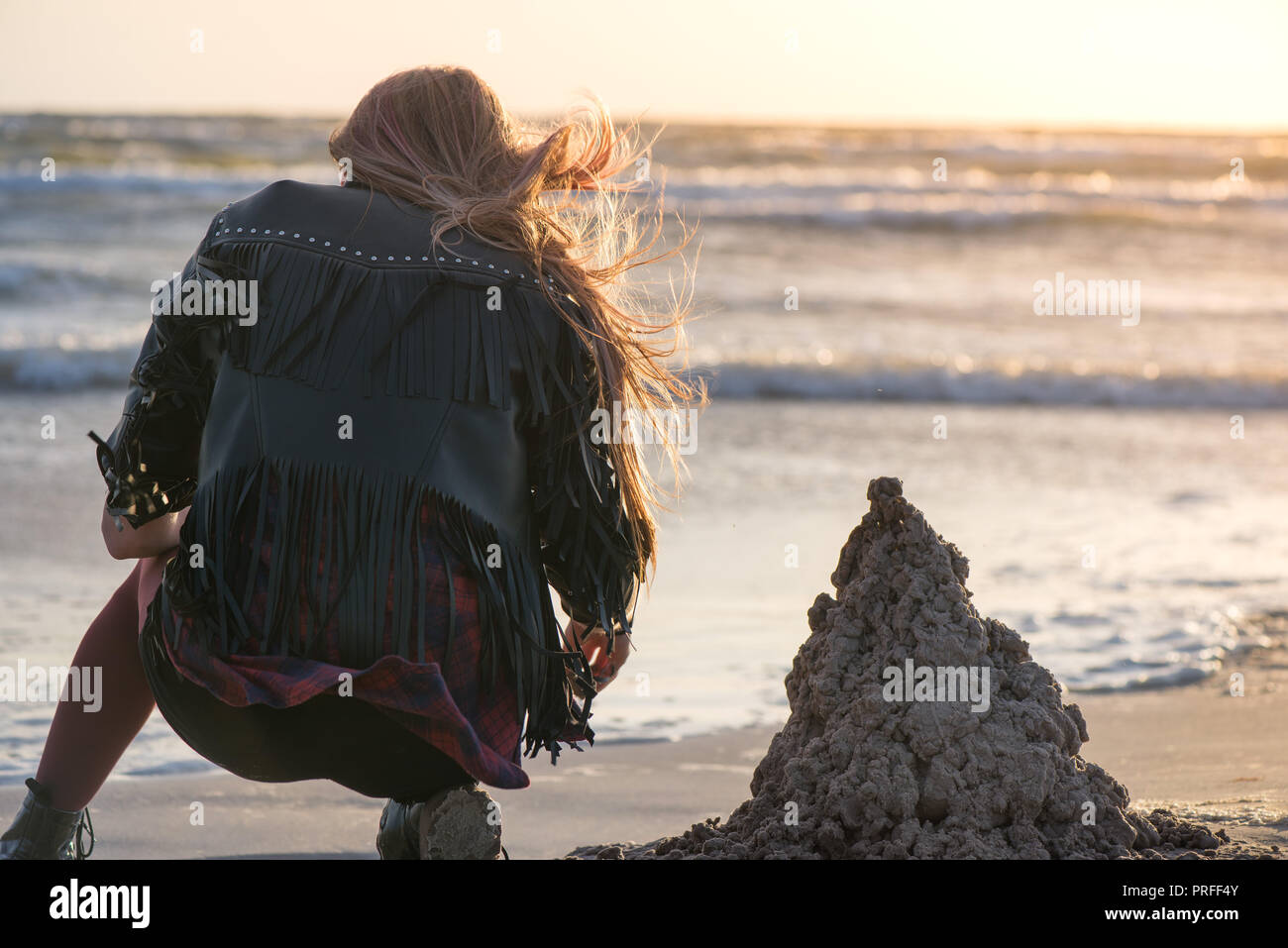 Young woman building and making sand castle next to sea. Calm, relaxing ...