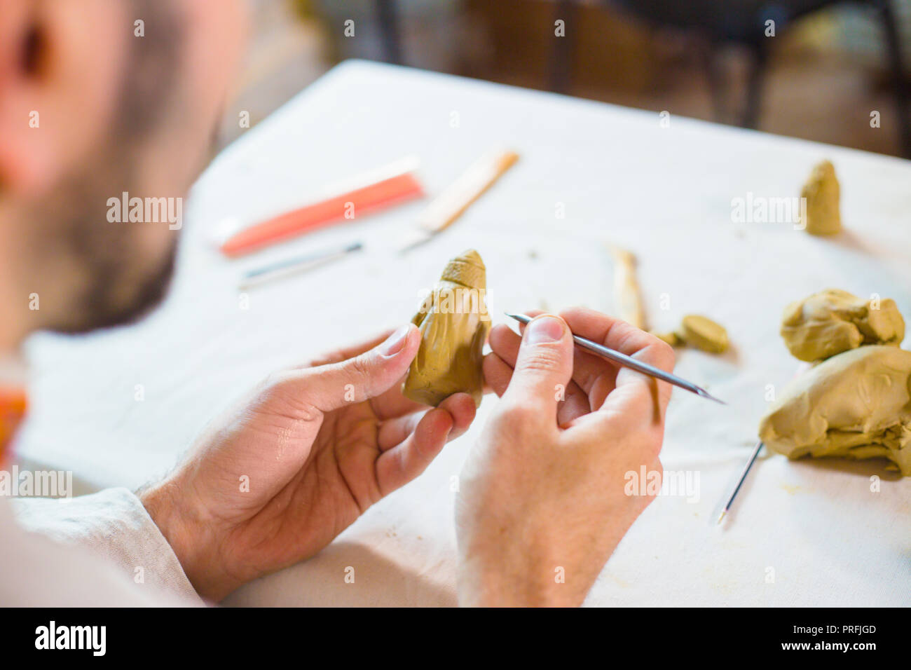 Professional male potter making clay figure for medieval popular ...