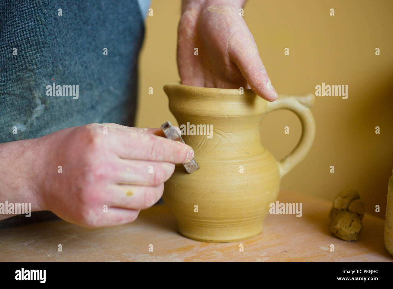 Professional potter making pattern on clay jar with special tool in ...