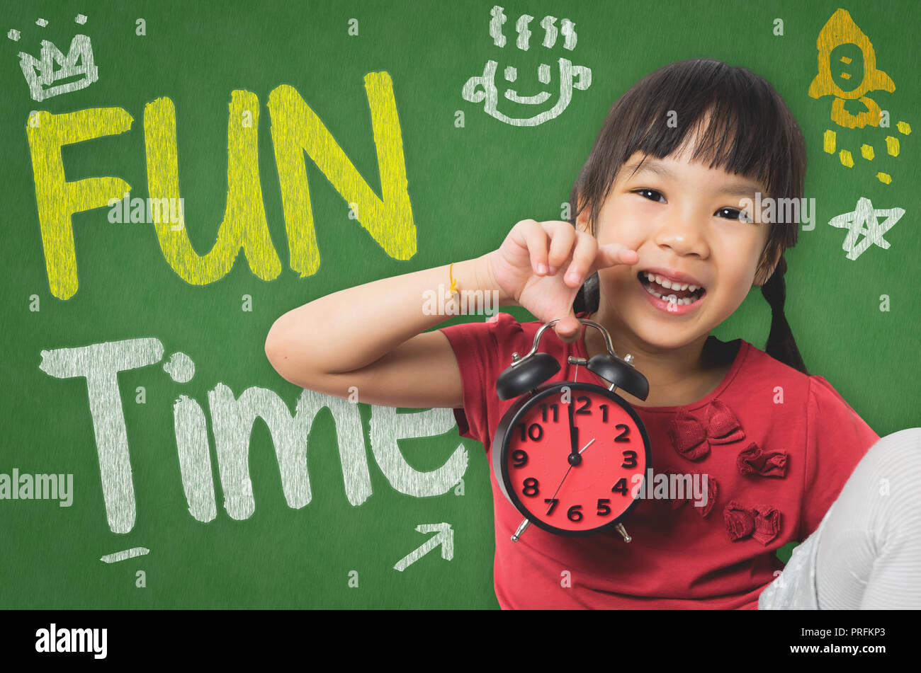 Girl holding a clock ready for fun time with drawing on blackboard ...