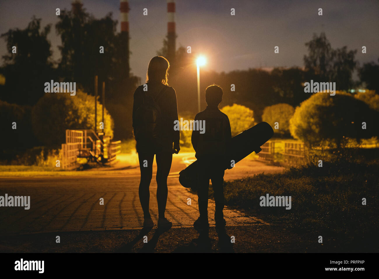 Woman with son riding on longboard in park at night time Stock Photo ...