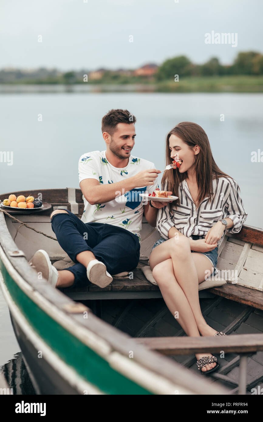 Romantic date. Man feeding his girlfriend cake. Happy attractive couple ...