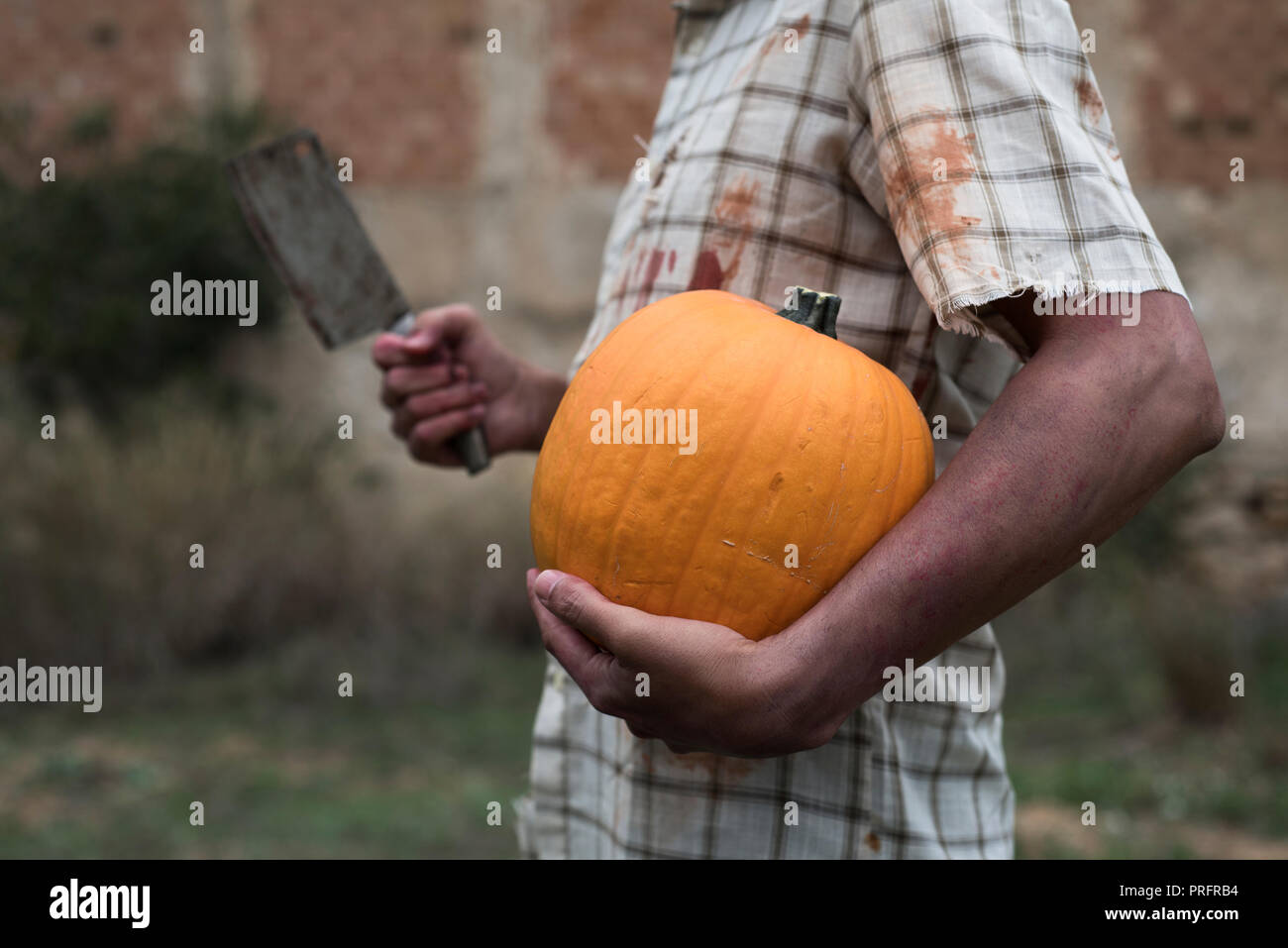 closeup of a scary man wearing dirty and ragged clothes with a pumpkin ...
