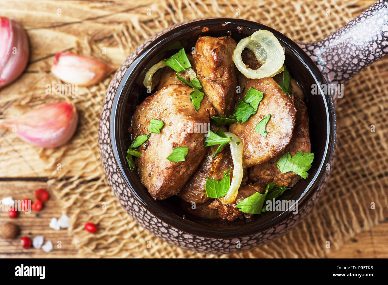 Baked chicken liver with onion in a ceramic cocotte on a wooden rustic ...
