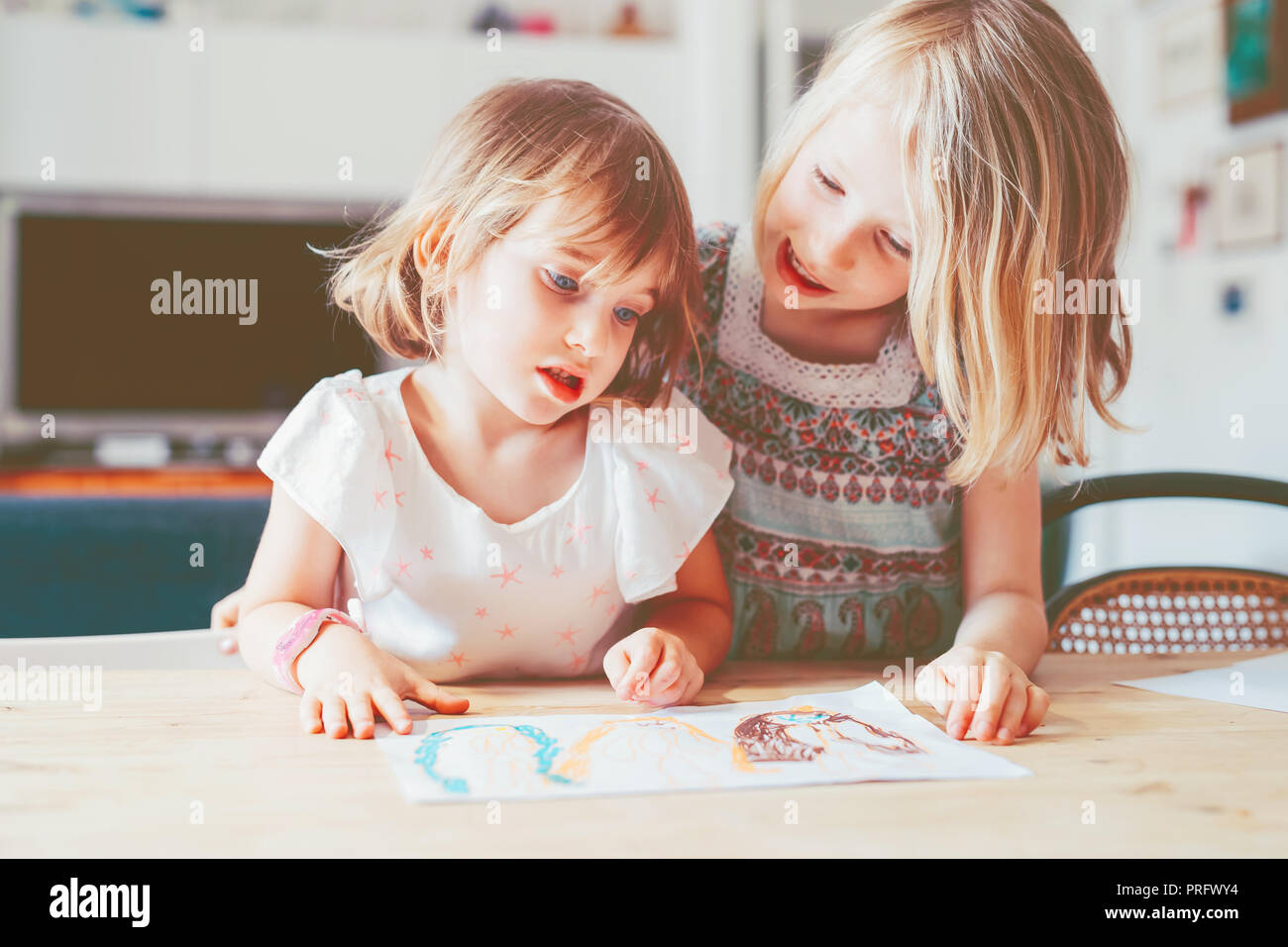 two female siblings children indoor drawing on a paper - playing ...