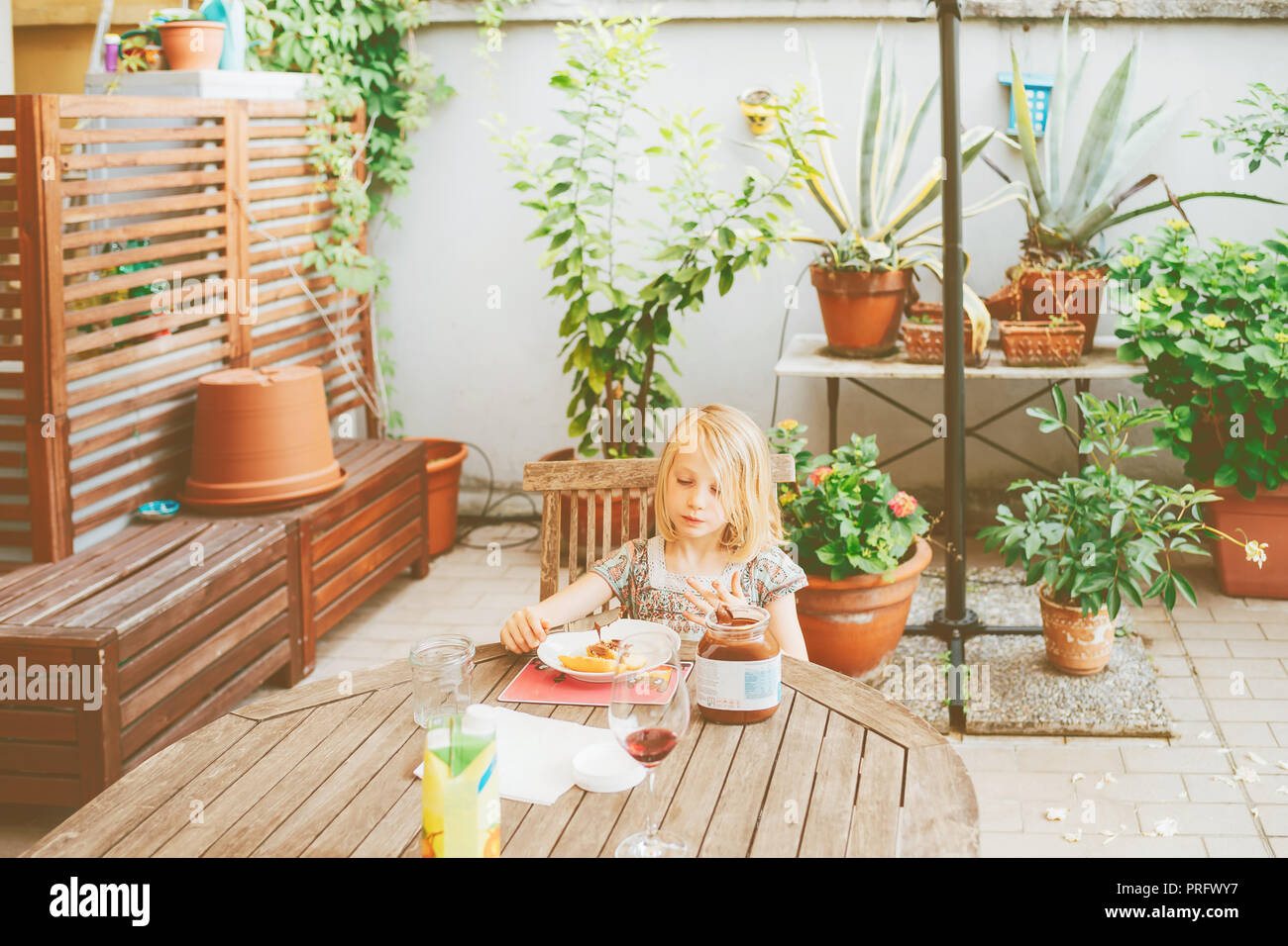 female child outdoor sitting table having breakfast - morning routine ...