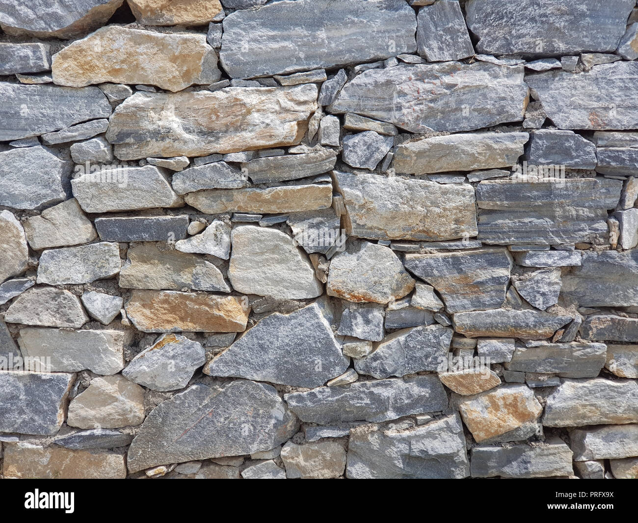 Granite wall made of stacked pieces stones. Full frame image as ...