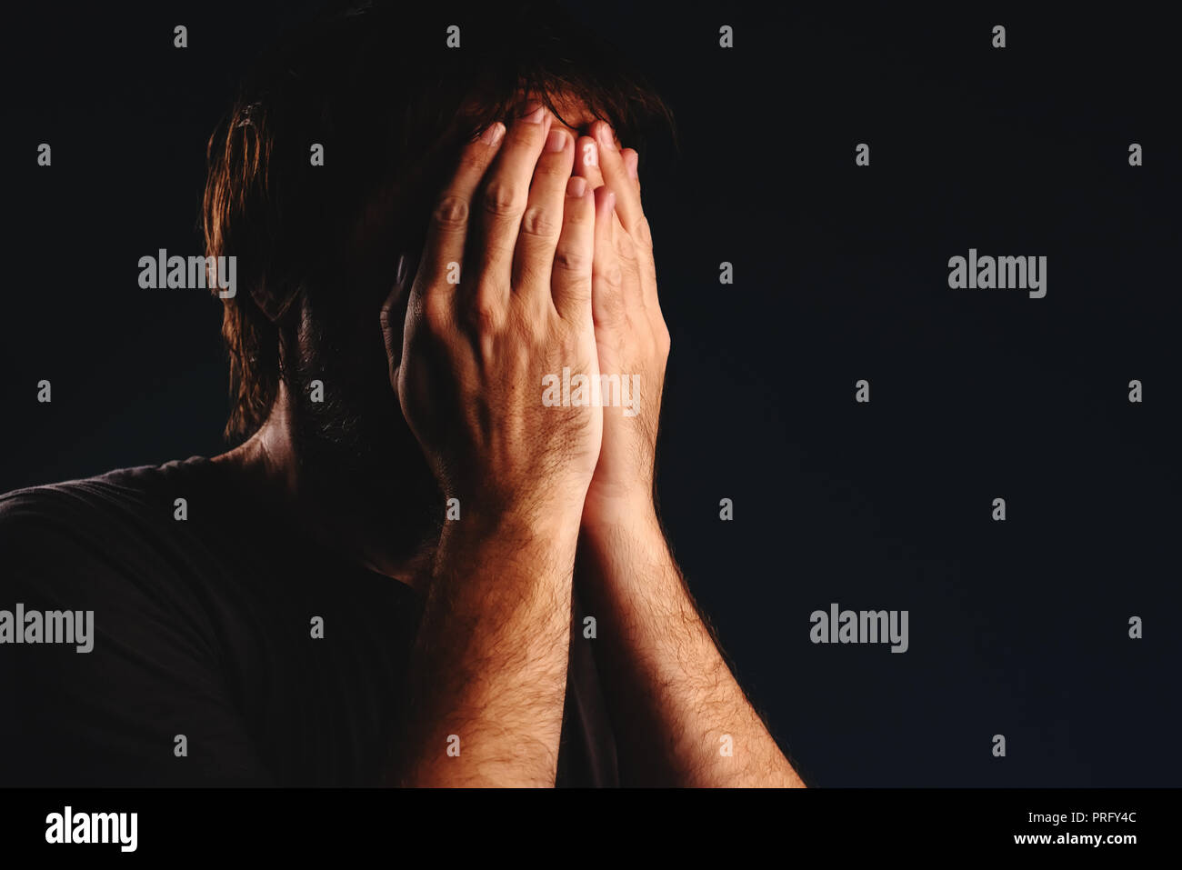 Man is crying in despair, hands covering face, low key portrait Stock ...