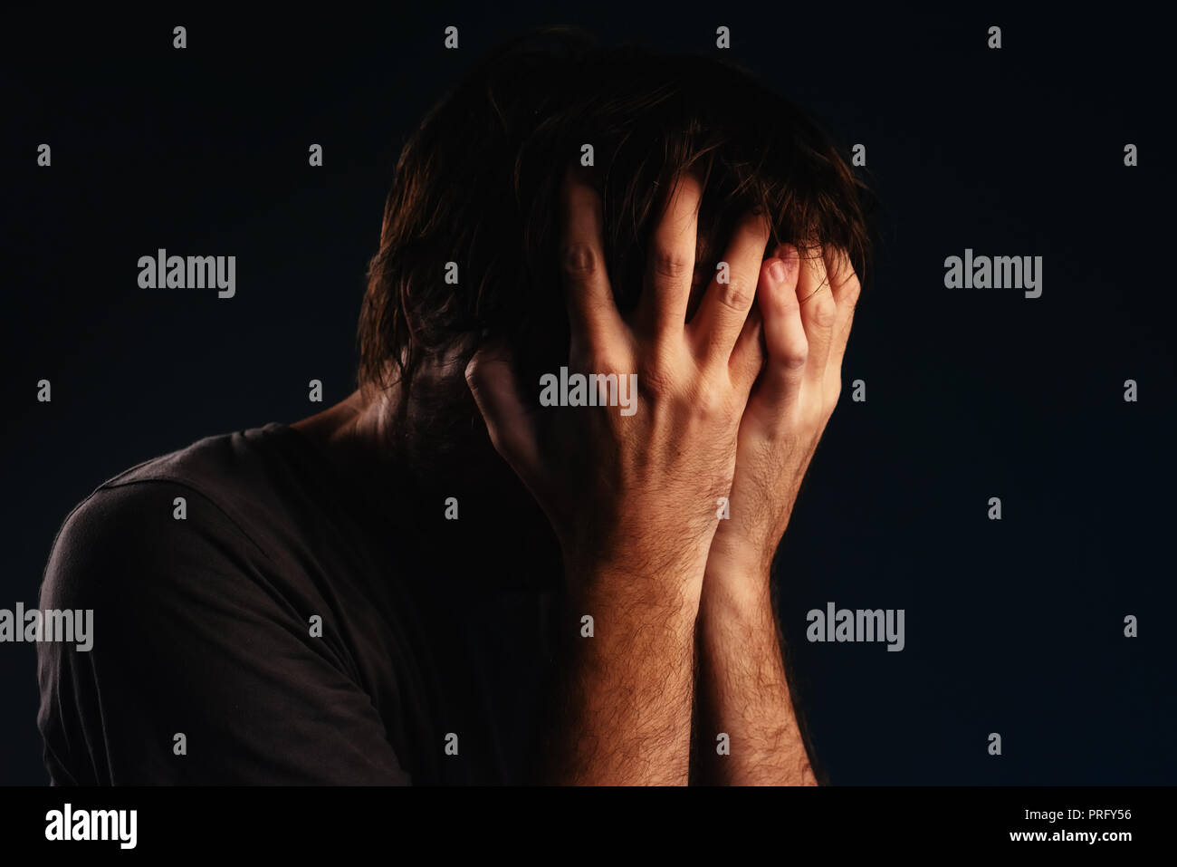 Man is crying in despair, hands covering face, low key portrait Stock ...