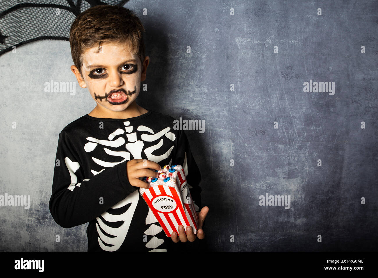 Little kid in a skeleton costume eating fake eyes on Halloween Stock ...
