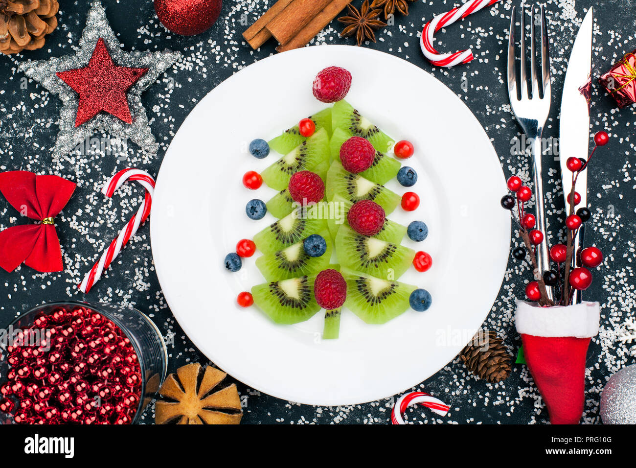 Kiwi christmas tree with raspberry, blueberry and cowberry on table ...