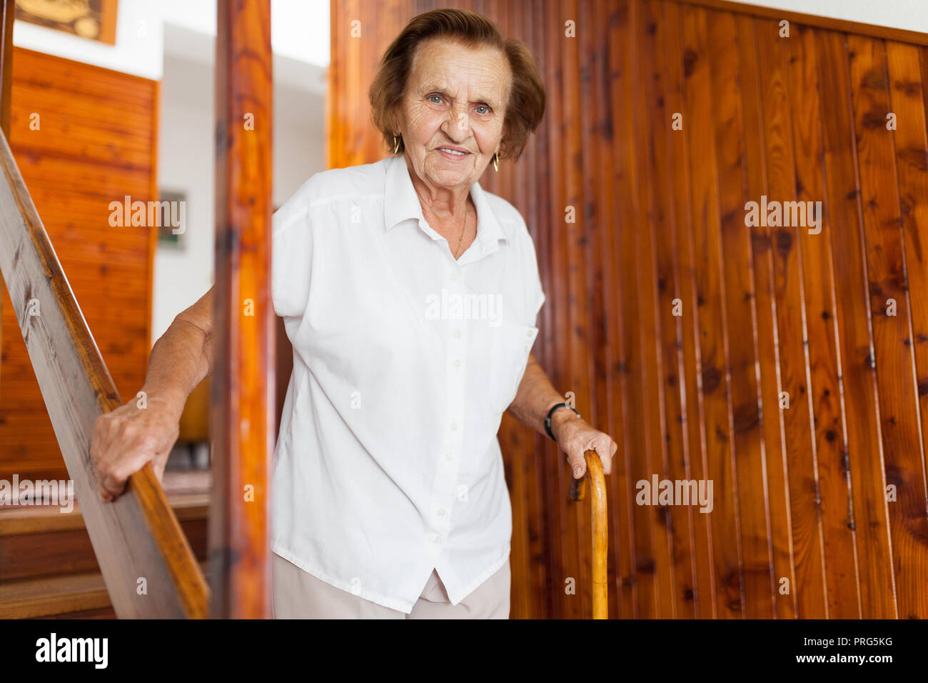 Elderly woman at home using a walking cane to get down the stairs Stock ...