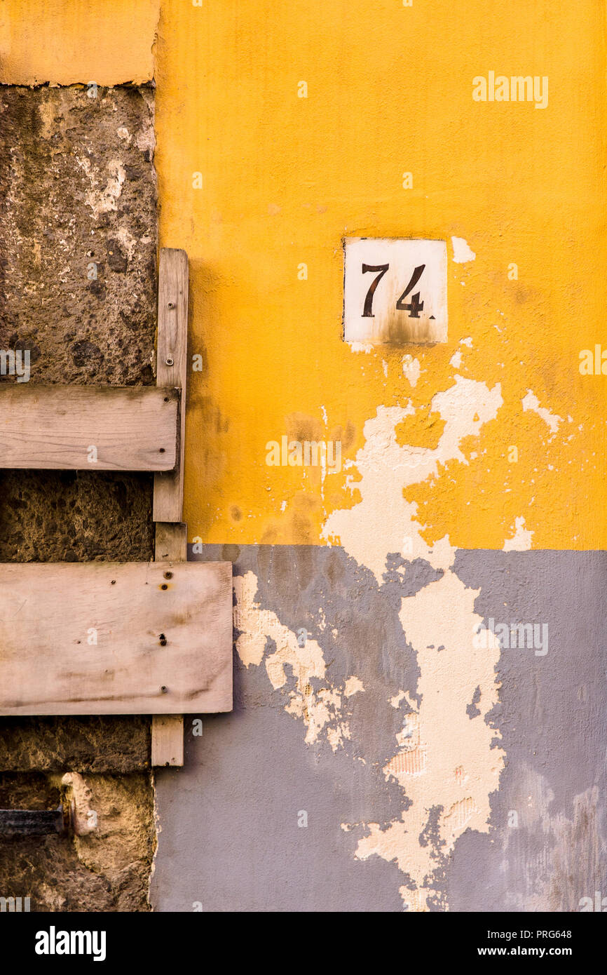 Crumbling yello and blue wall with a '74' house number sign on Procida ...
