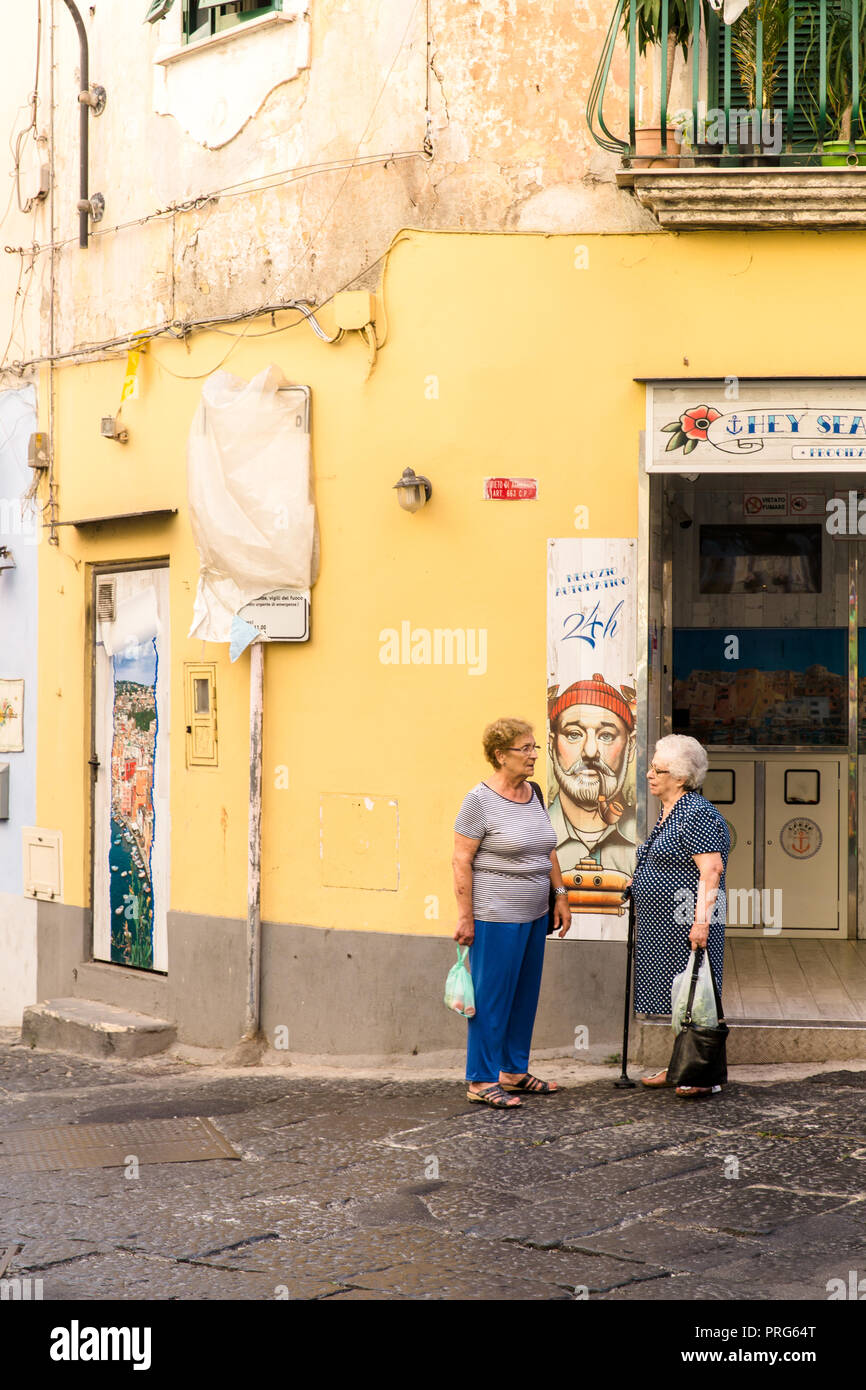 Two women chatting on a street corner in Procida Island, Naples, Italy ...
