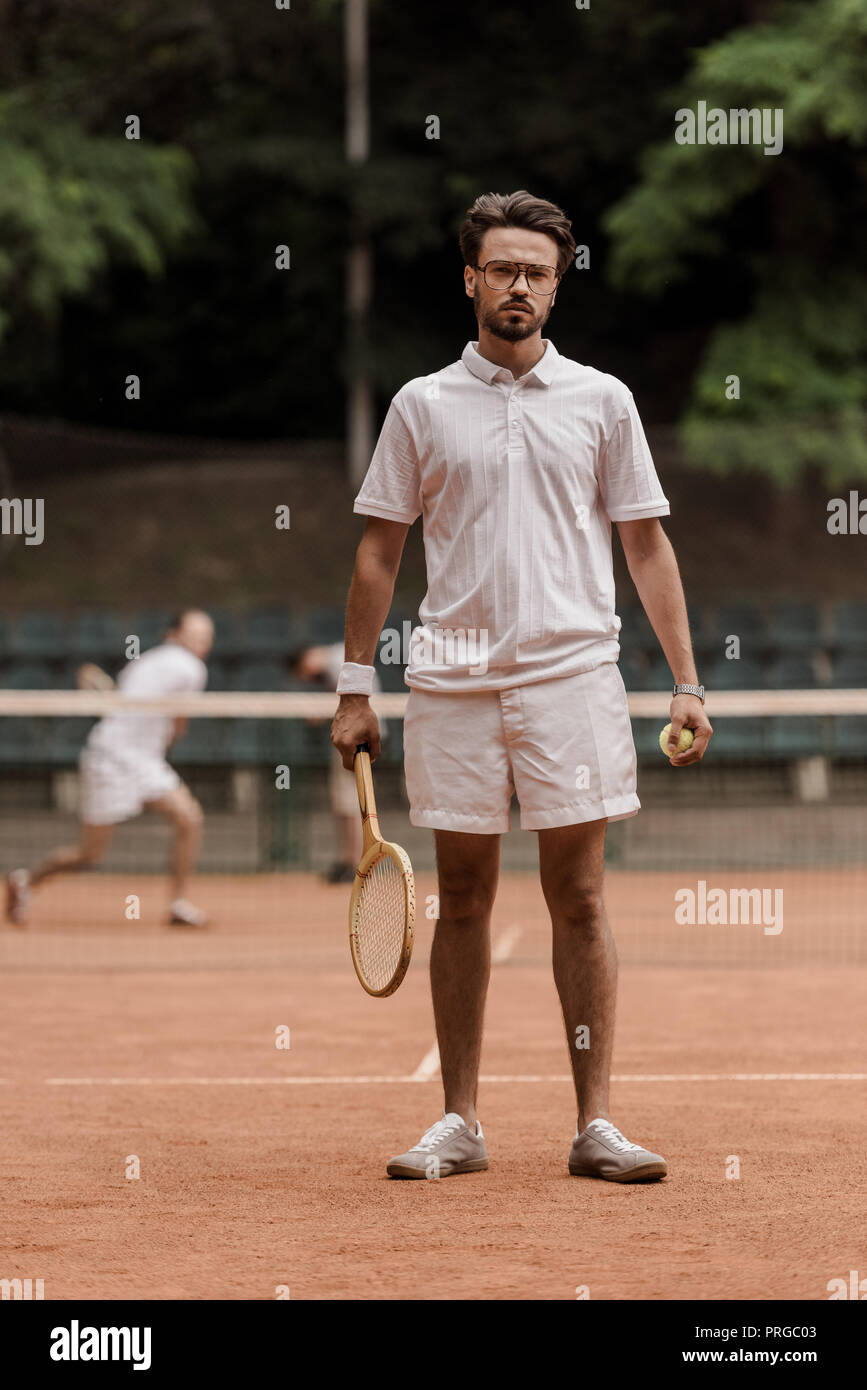 retro styled tennis player standing with racket and ball at court Stock ...