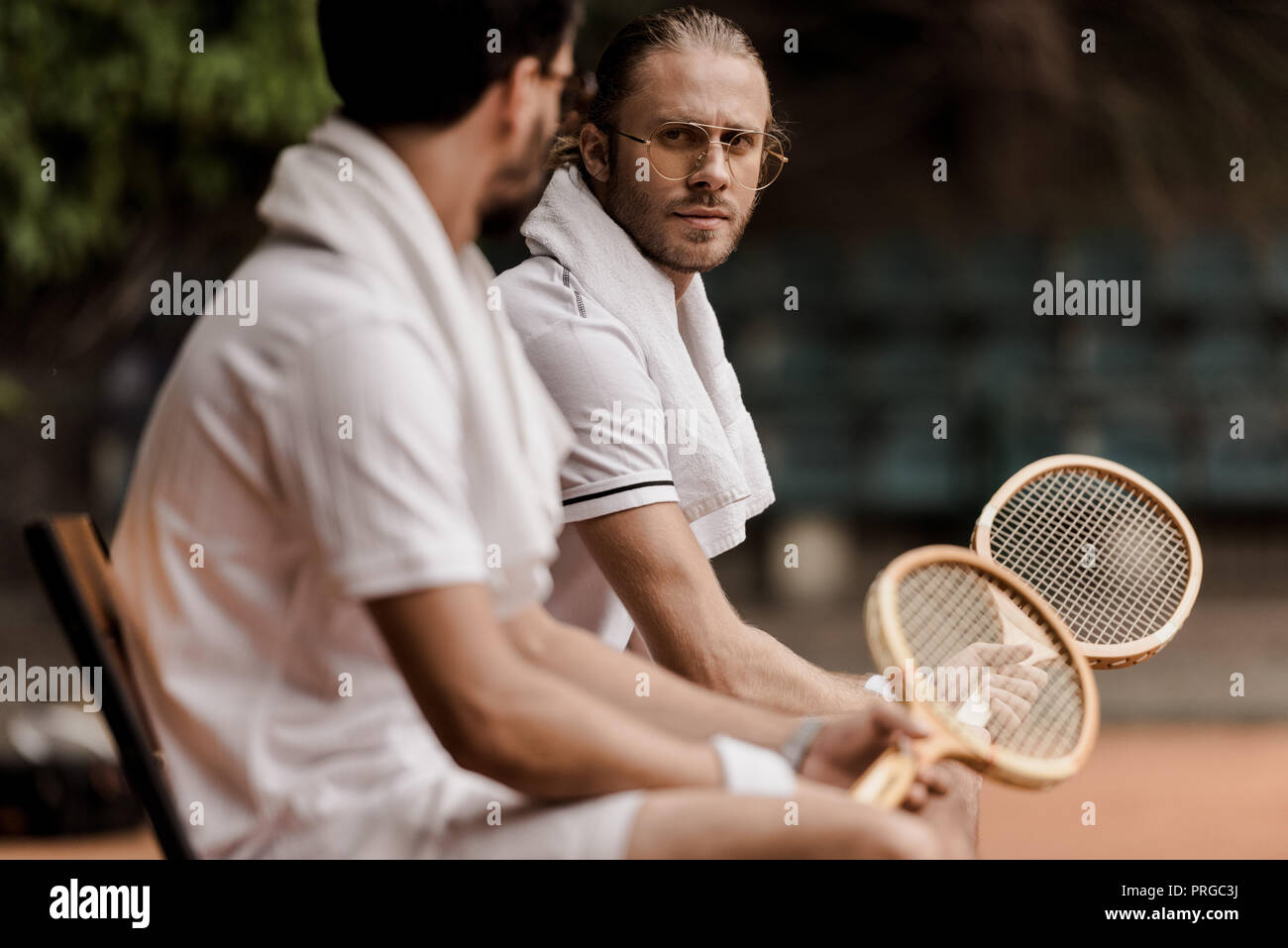 retro styled tennis players resting on chairs with towels and rackets ...