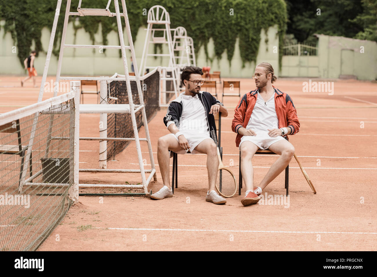 retro styled tennis players resting on chairs at tennis court Stock ...
