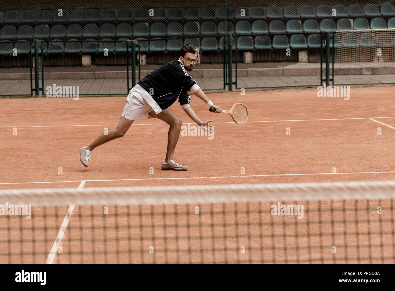 retro styled handsome man playing tennis with racket at tennis court ...