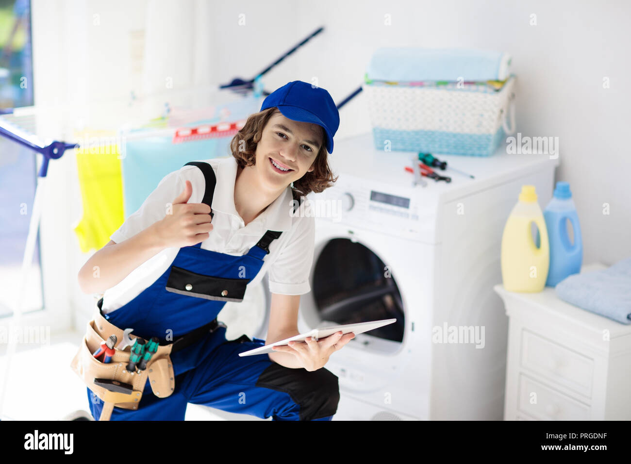 Washing machine repair service. Young male technician in blue uniform ...