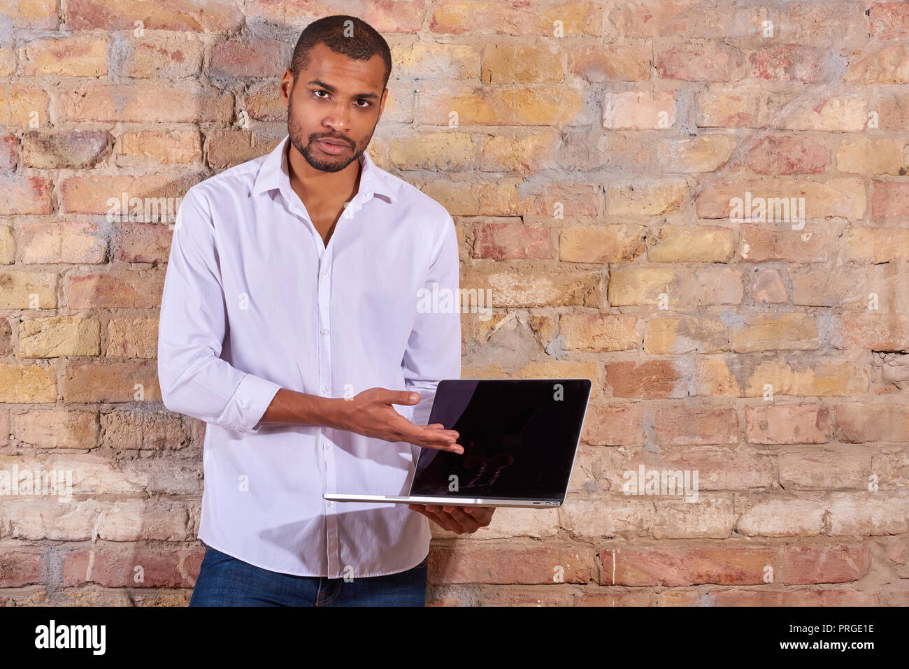 A serious handsome young man pointing to the screen of his laptop in a ...