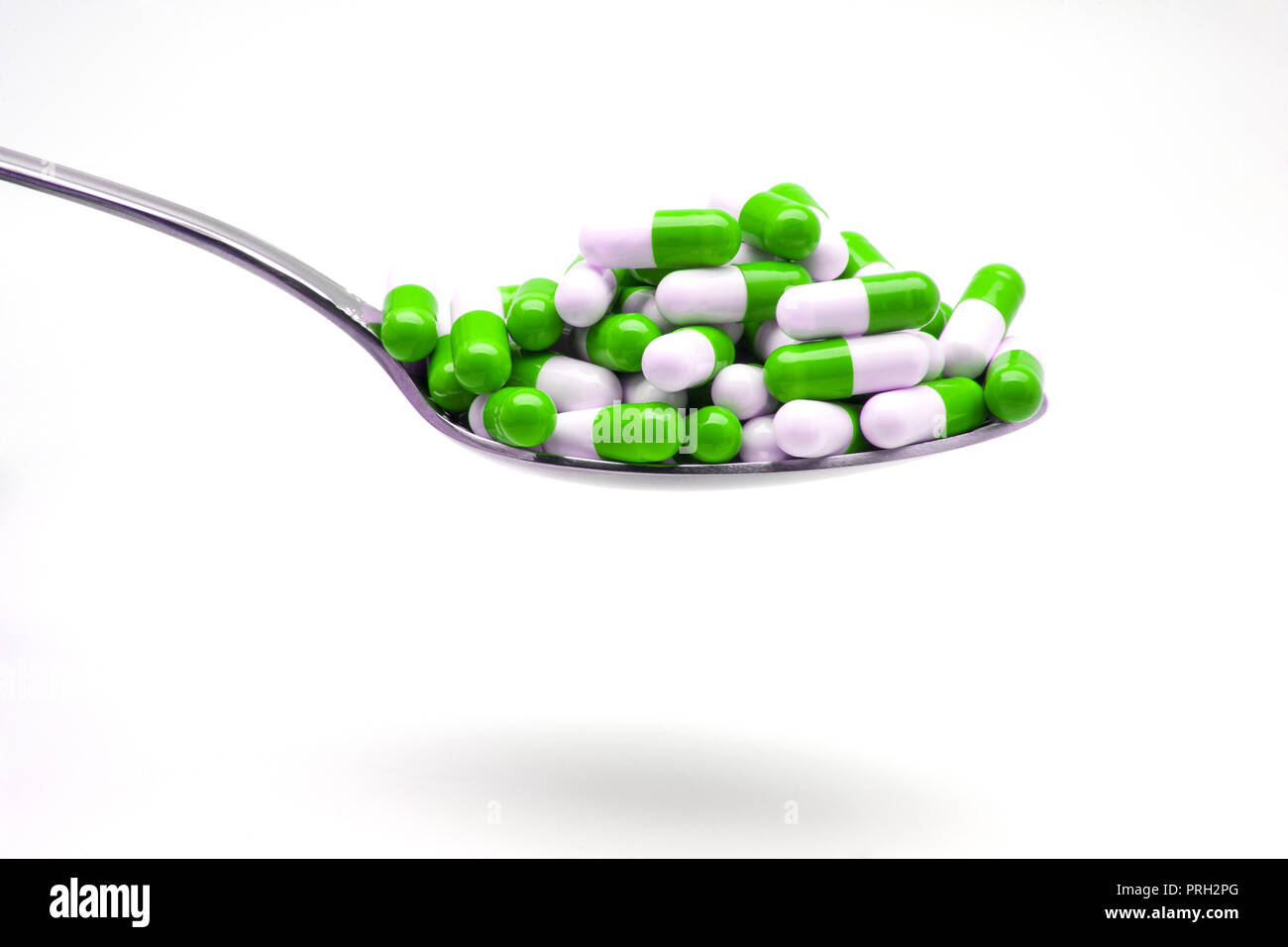 spoon with green capsules on white fund Stock Photo - Alamy
