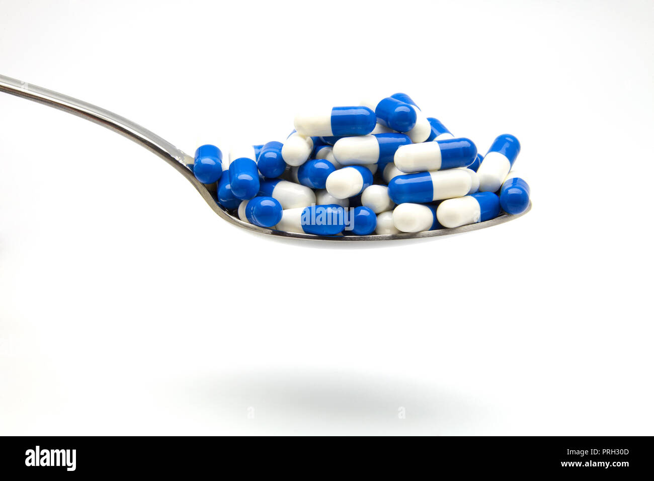 Blue capsules in silver spoon Stock Photo - Alamy