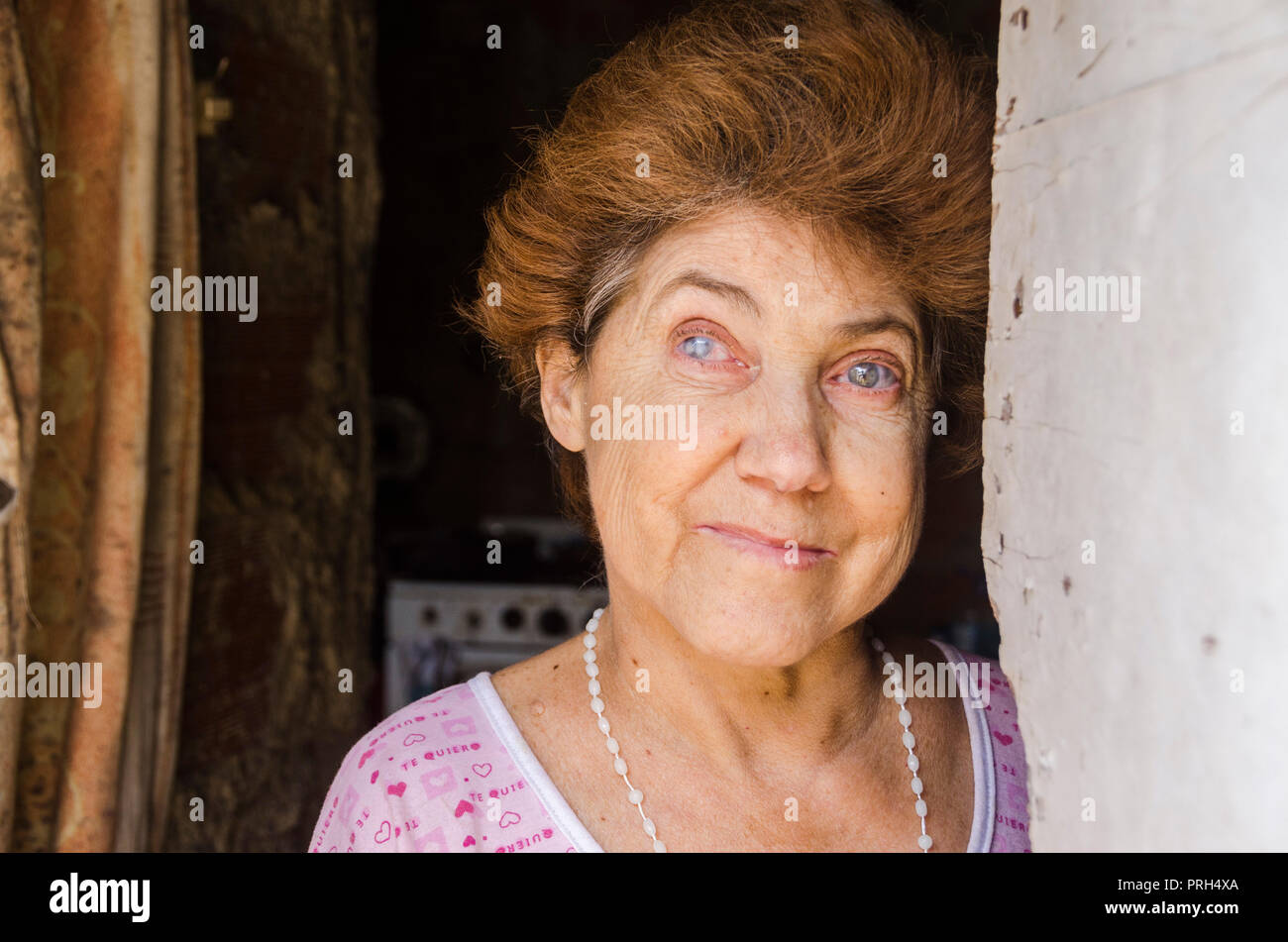 A lady with sight problems, looks out the door of her house in a rural ...