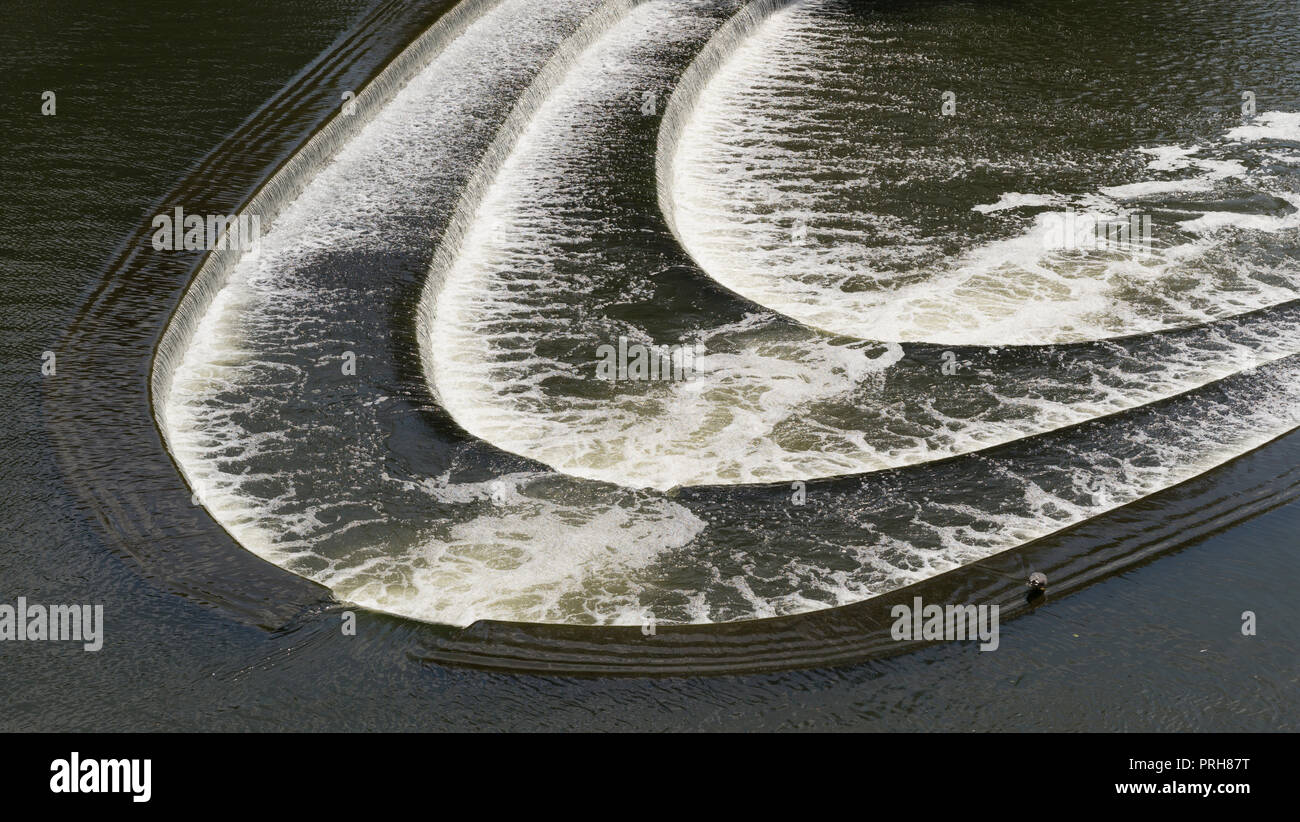 Water flowing in stages over 3-stage curved weir in River Avon Stock ...