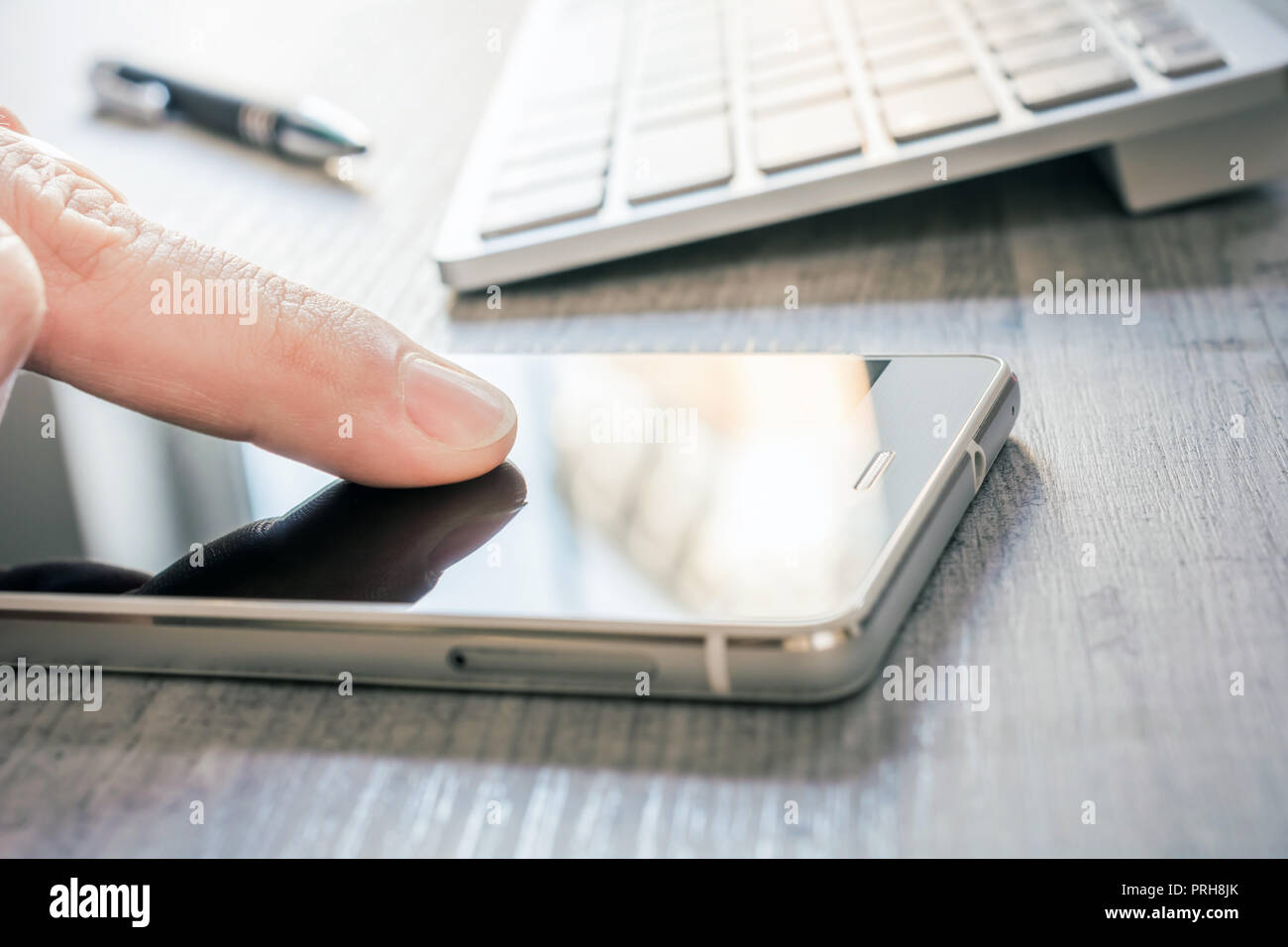 Finger Touching Mobile Phone With Reflection Next To A White Keyboard ...