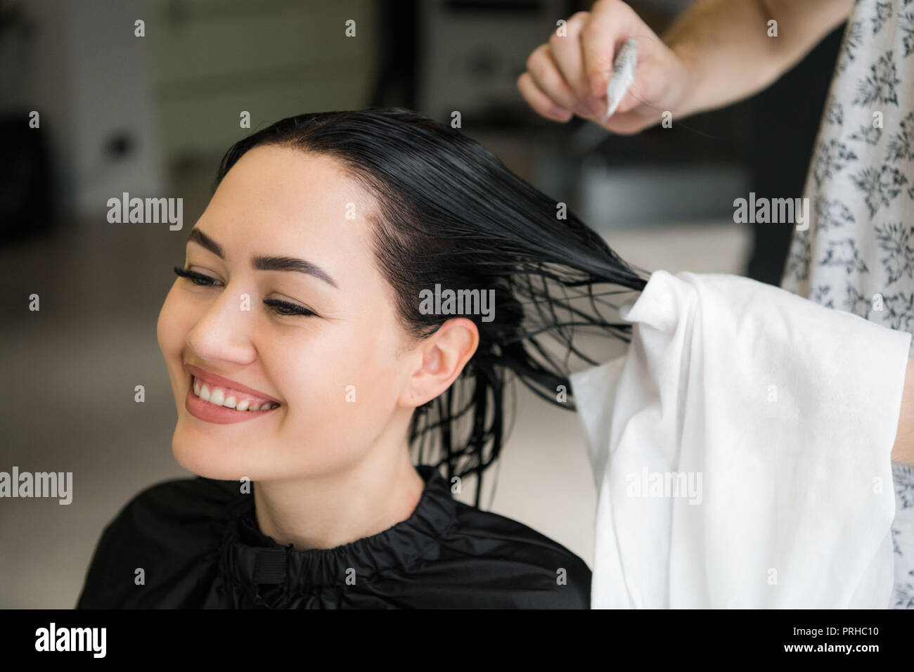 Hairdresser cutting woman's hair in salon, smiling, front view, close ...