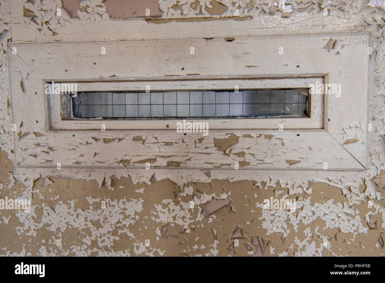 Narrow window on the door of a prison cell with old, peeling paint ...