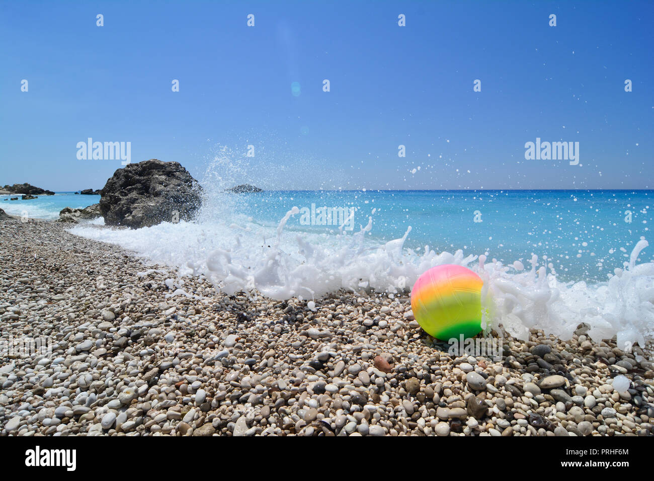 Colorful ball on a pebble beach sprayed with waves and sea foam Stock ...