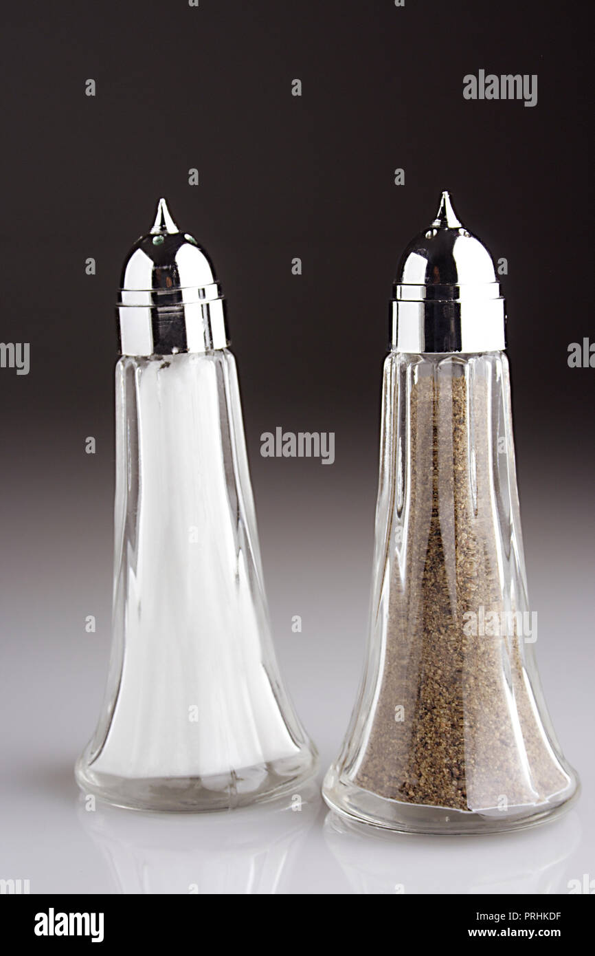 Salt and pepper in glass shakers Stock Photo - Alamy