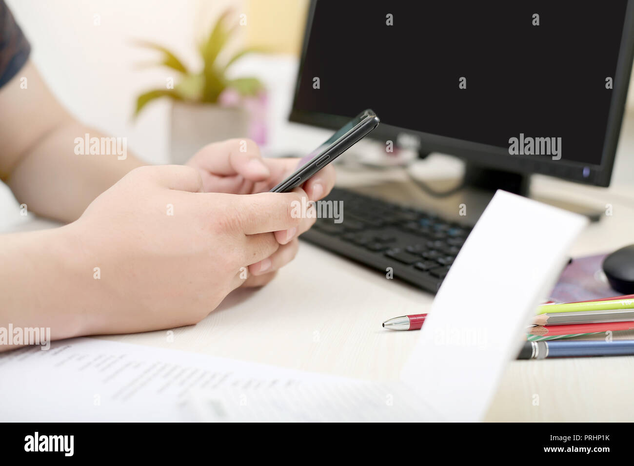 Man is using smartphone in hand. Picture of notepad, pencil, keyboard ...