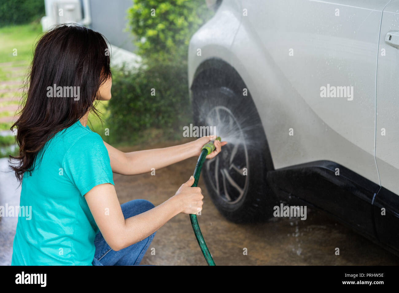 Young woman water spray her car wheel with water tube washing it Stock ...