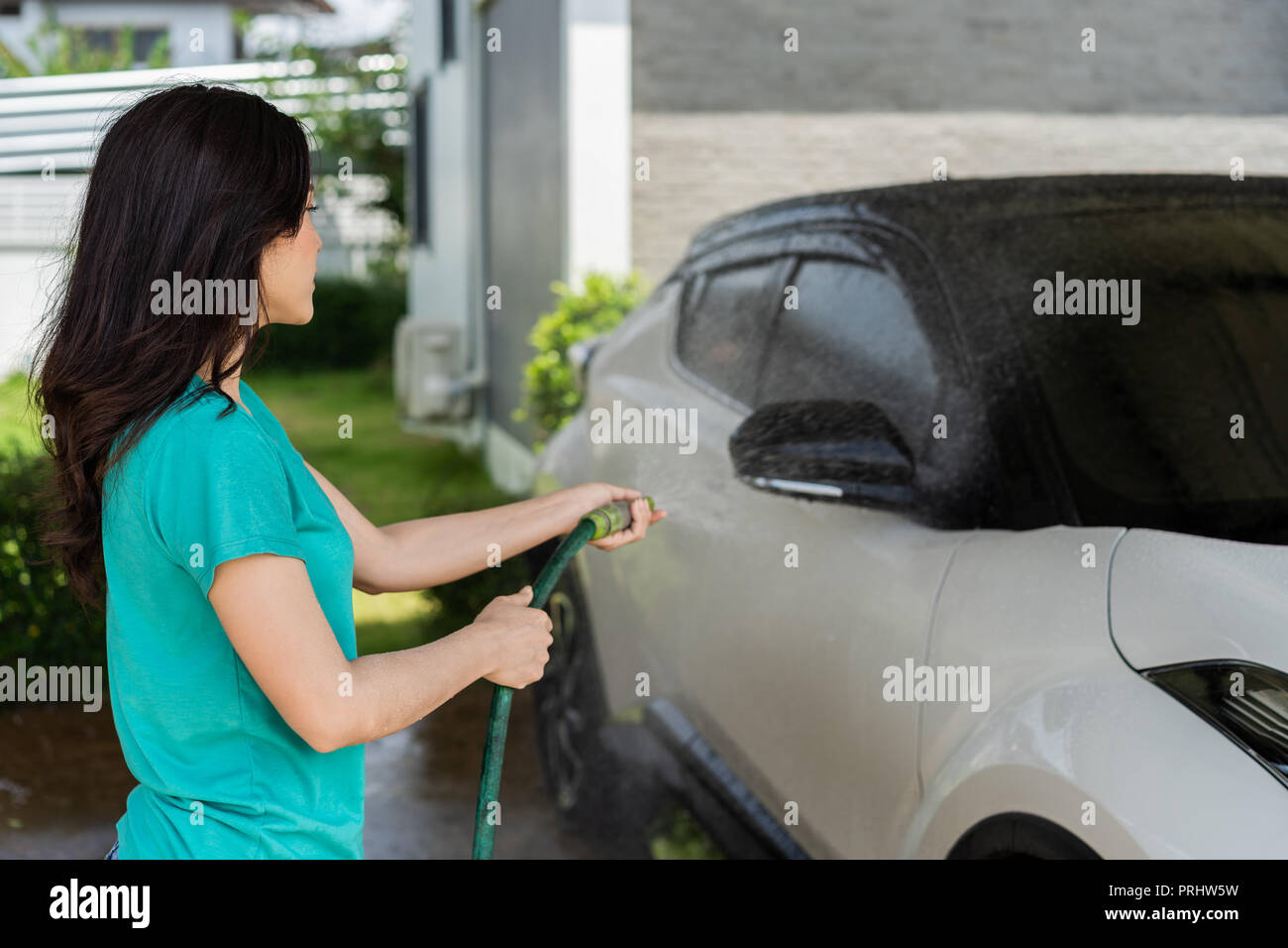 Young woman water spray her car with water tube washing it Stock Photo ...